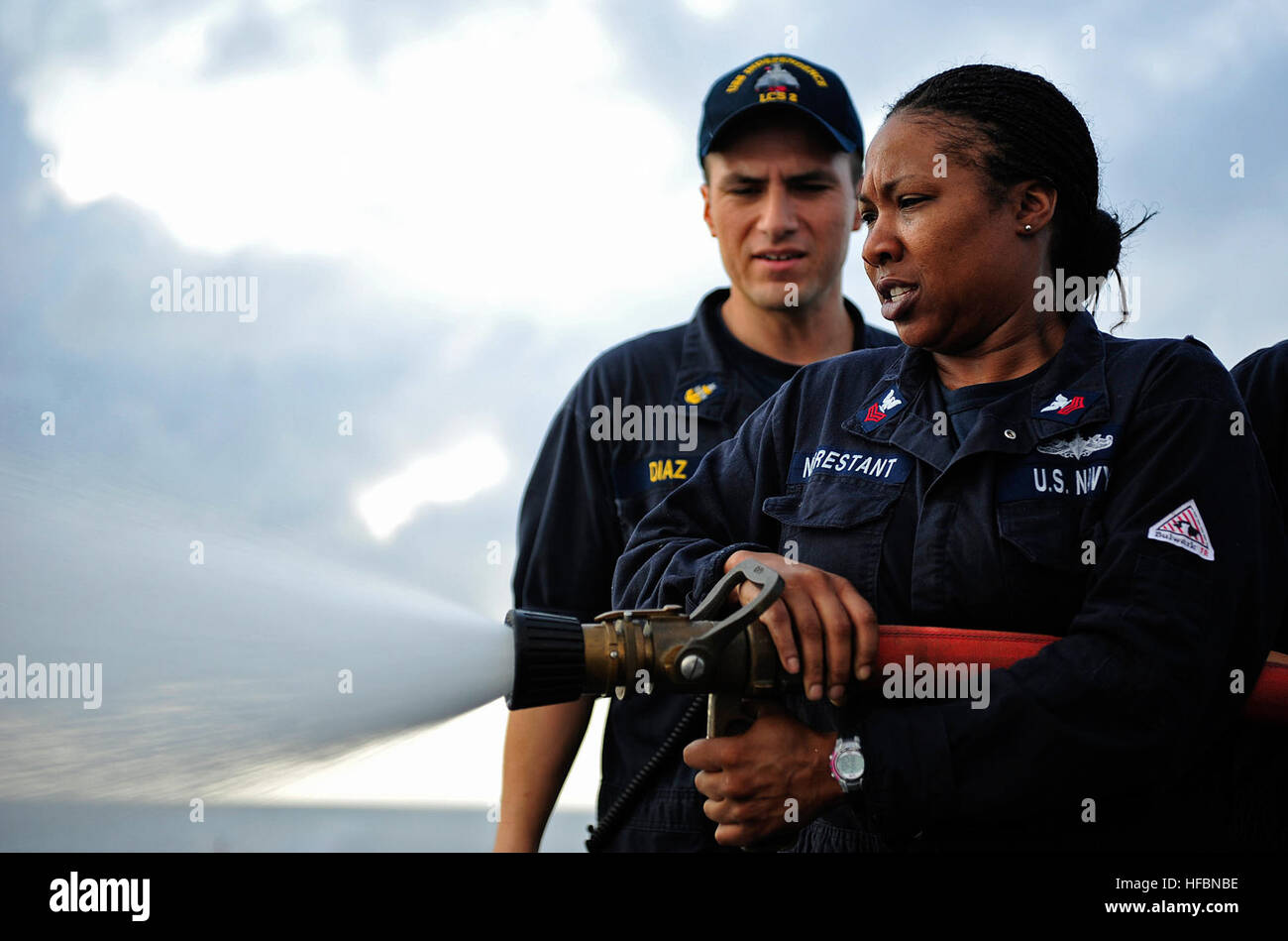 A Culinary Specialist practices using a firefighting hose under the ...