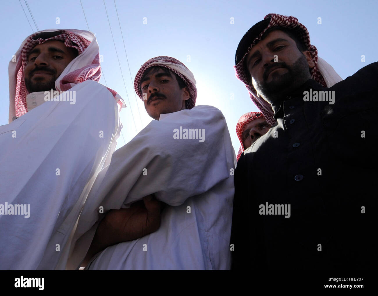 Iraqi men wait in line outside the government headquarters building to ...