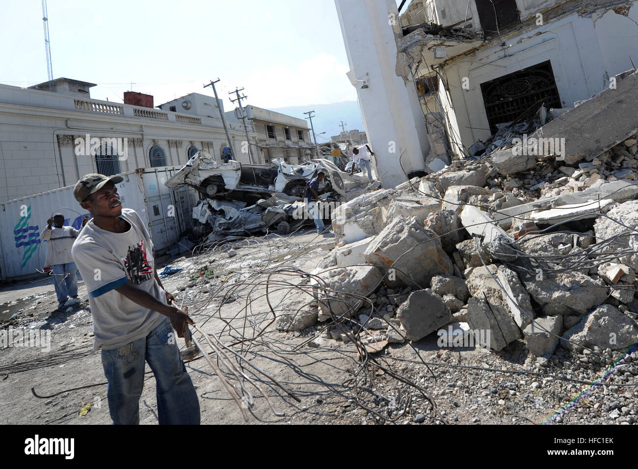 An earthquake survivor removes debris from a devastated road in Port-au ...