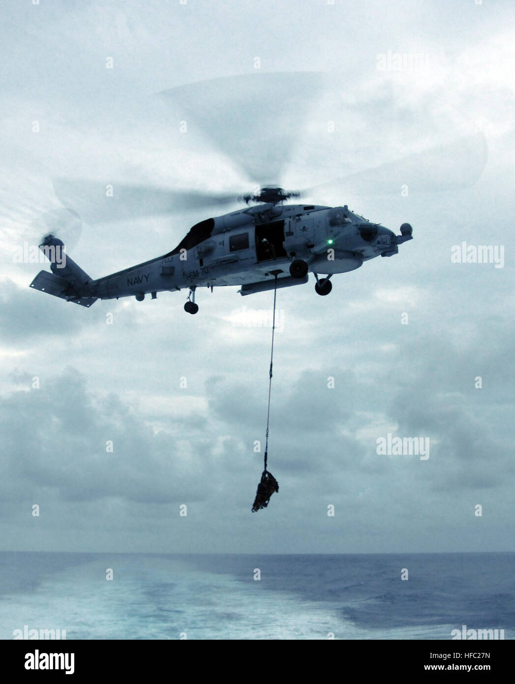 An MH-60R Seahawk from HSM-70 conducts a vertical replenishment from ...