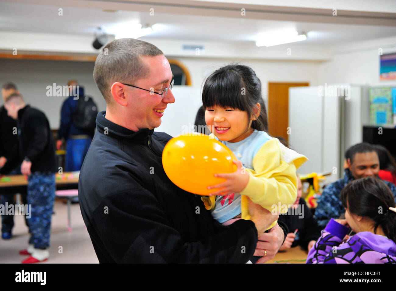 Religious Program Specialist 1st Class Brian Jewell holds a child as U ...