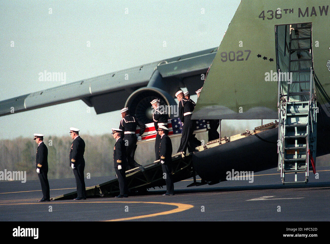 Descending from the nose of a C-5 Galaxy aircraft, pallbearers carry ...