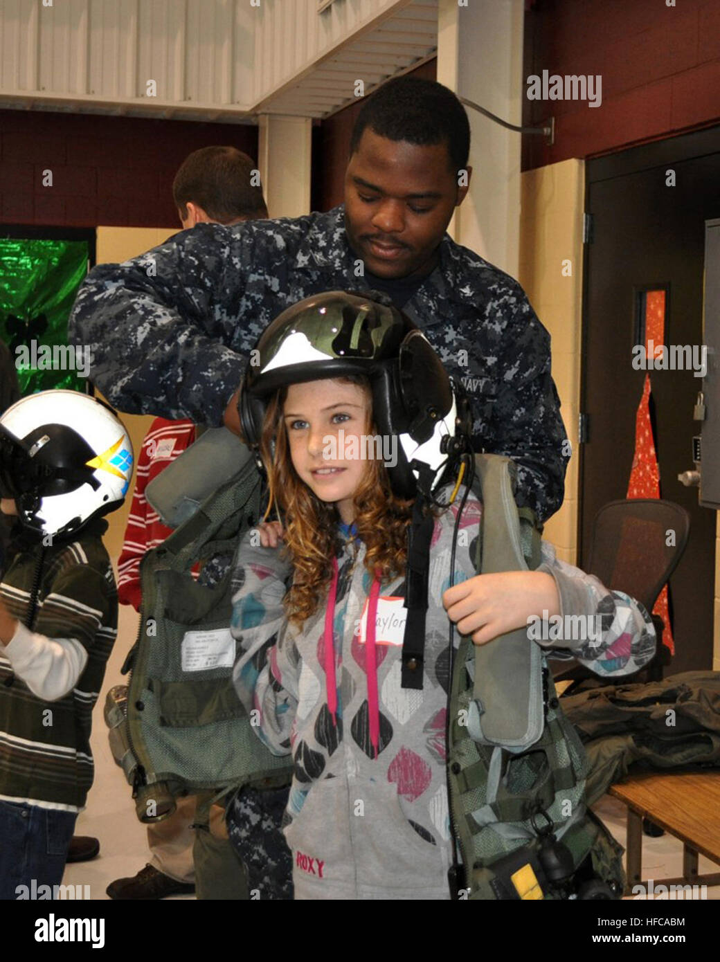 Petty Officer 3rd Class Donte Nickerson, parachute rigger, helps a ...