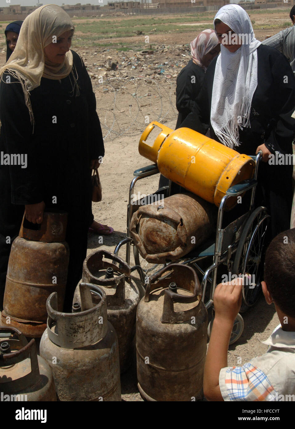 Residents of the Al Haytar region of Baghdad carry empty propane tanks ...