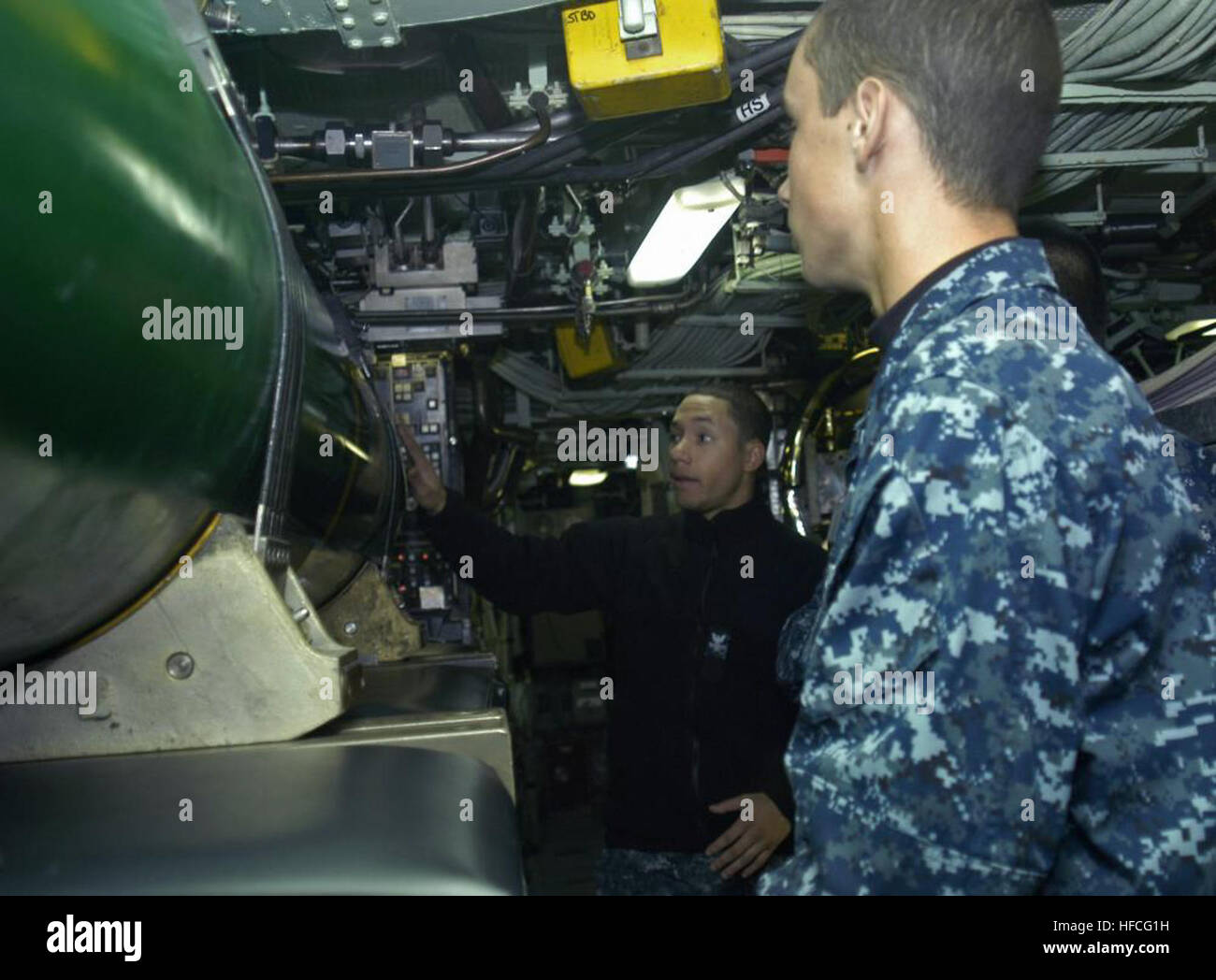 A Navy Fire Control Technician demonstrates a torpedo to members of the ...