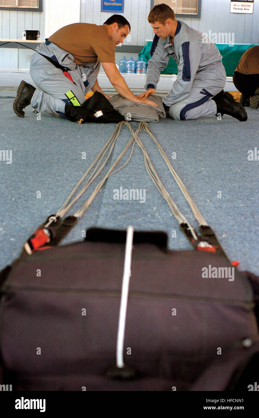 Students at parachute school pack chutes under supervision, assisted by ...