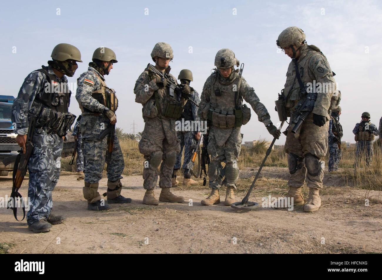 U.S. Army Spc. Steven Whipple (right) finds a metallic object in a road ...