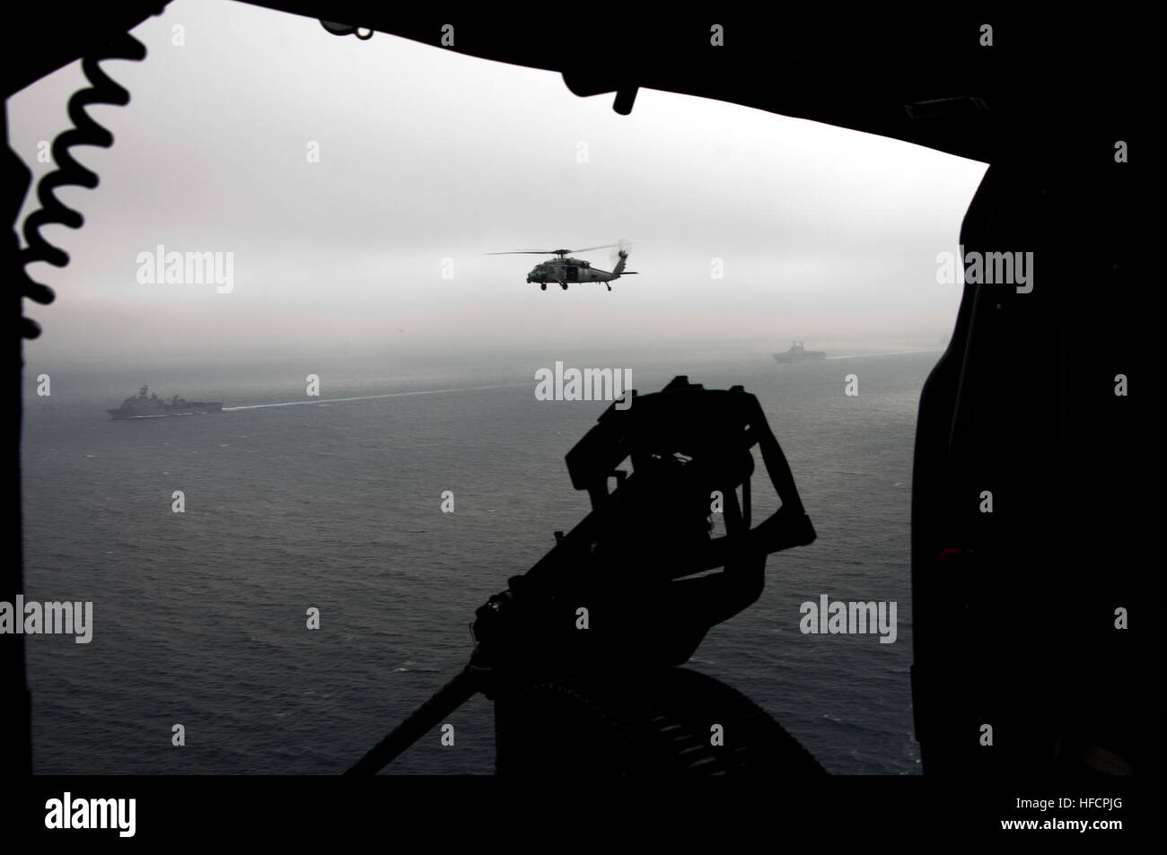 A U.S. Navy SH-60 Seahawk helicopter flies above the amphibious dock ...