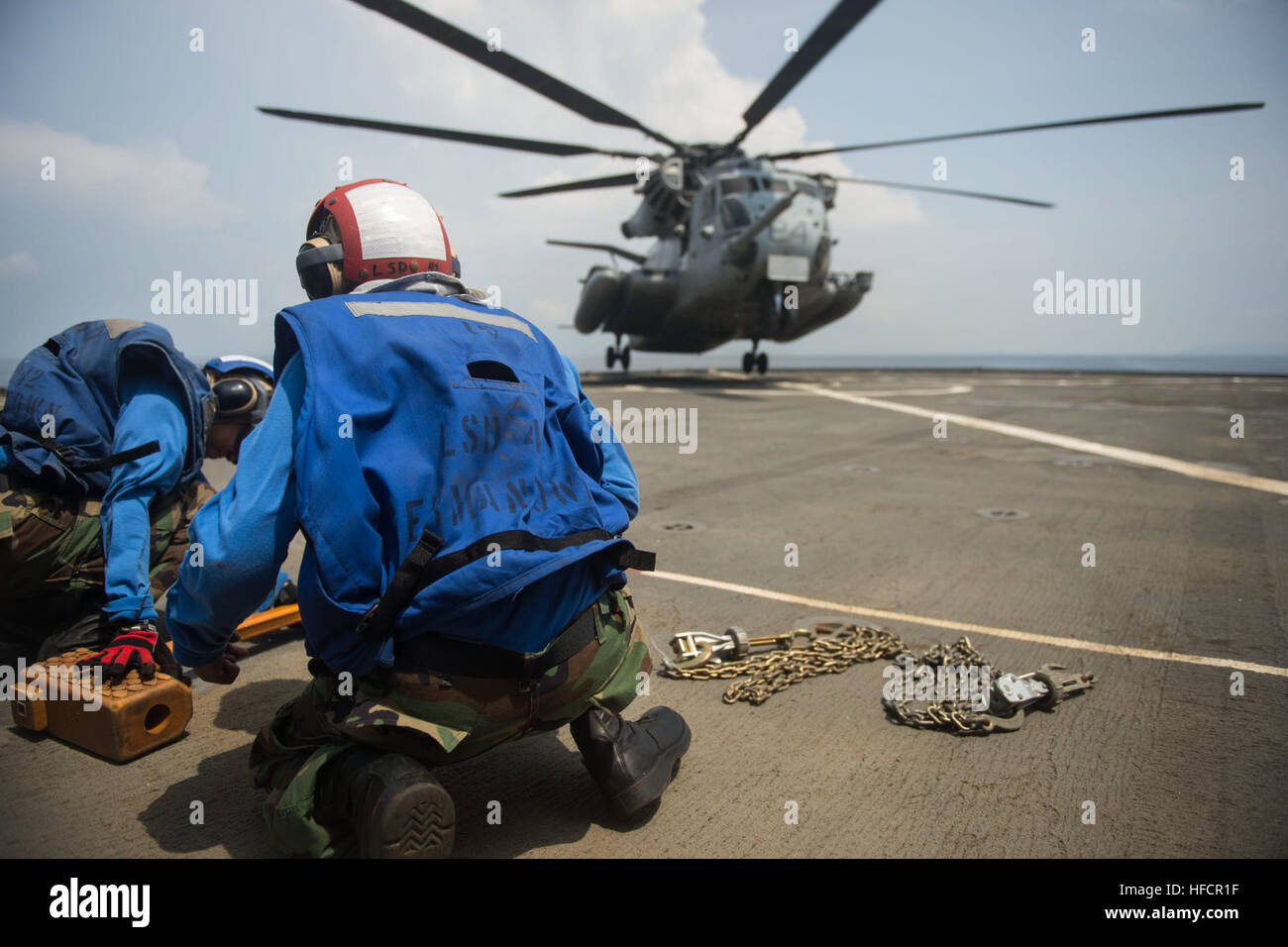 Sailors prepare to chock and chain a CH-53E Super Stallion, assigned to ...