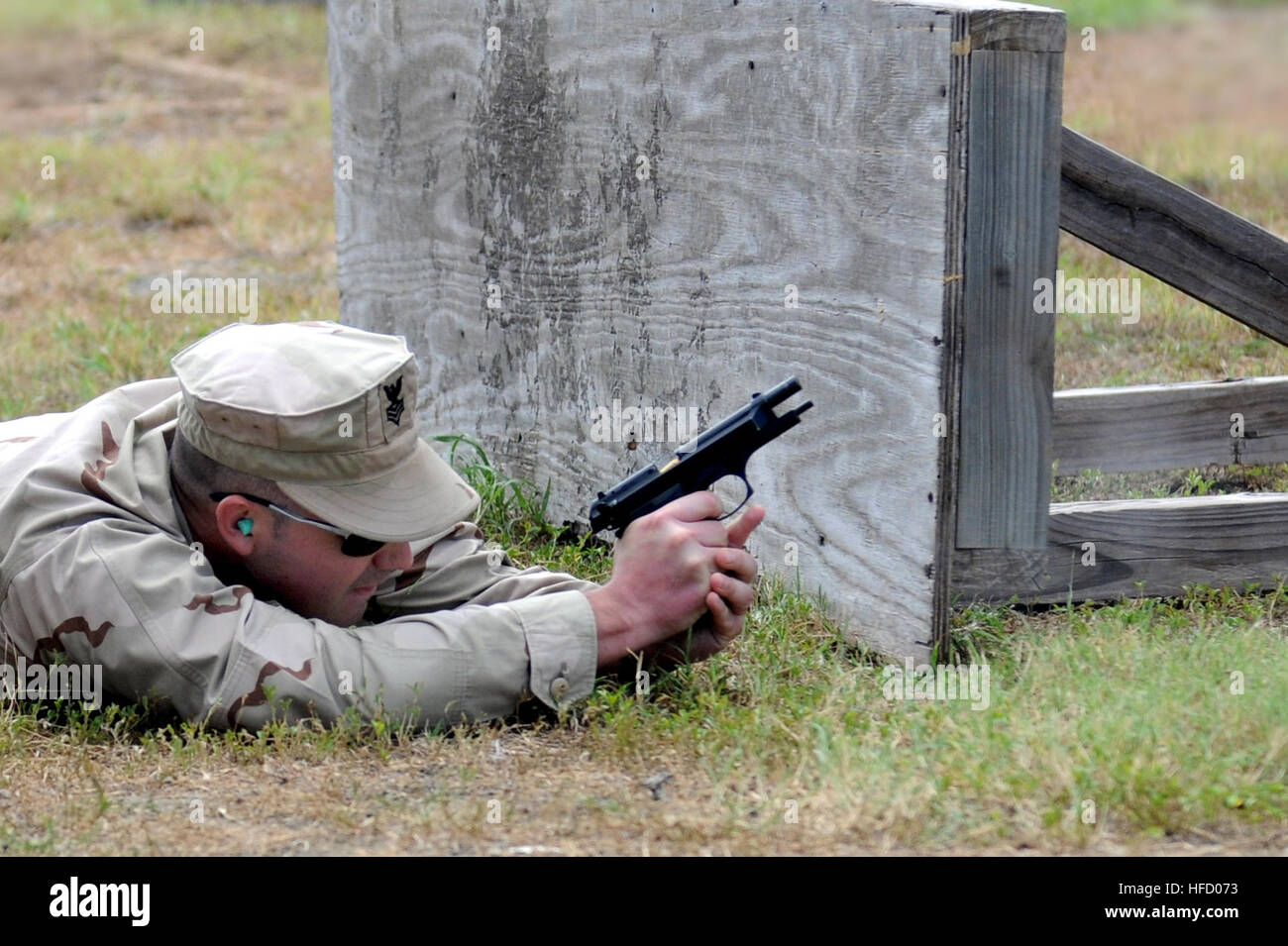 A Navy Master-at-Arms conducts weapons qualification with an M-9 pistol ...