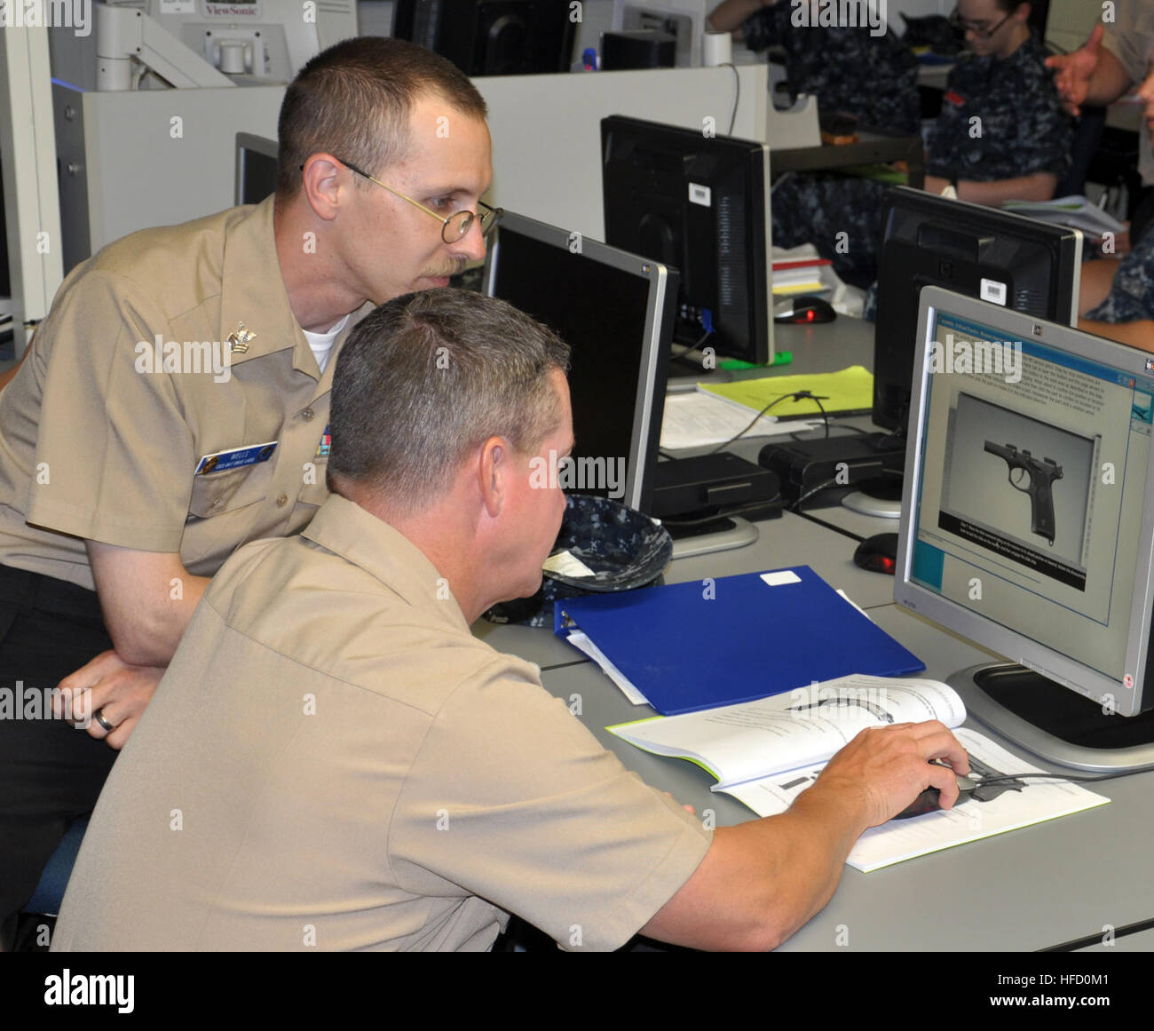 Petty Officer 1st Class Cody Wells looks over computer based training ...