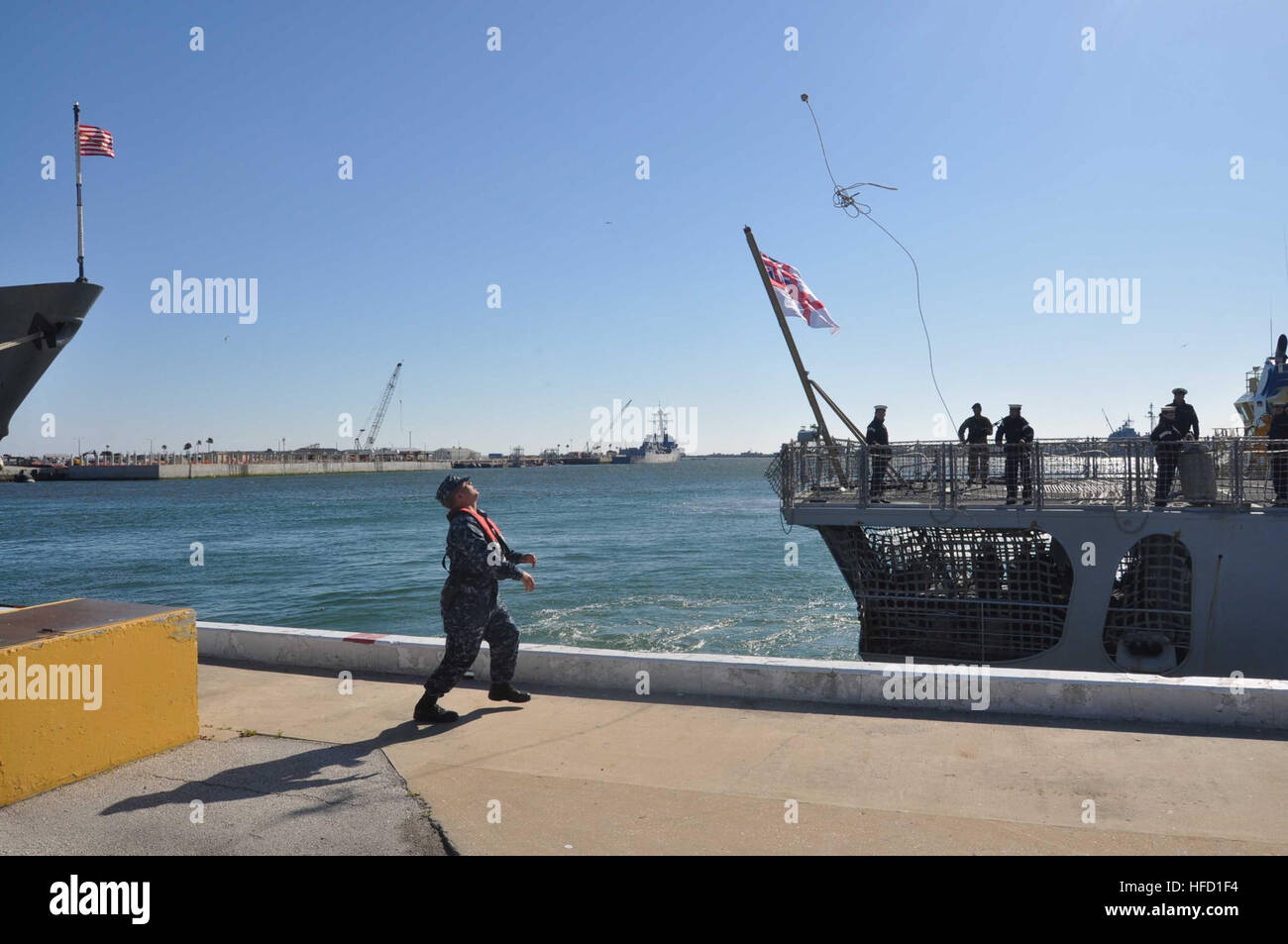 An U.S. sailor prepares to catch a line thrown by a British sailor ...