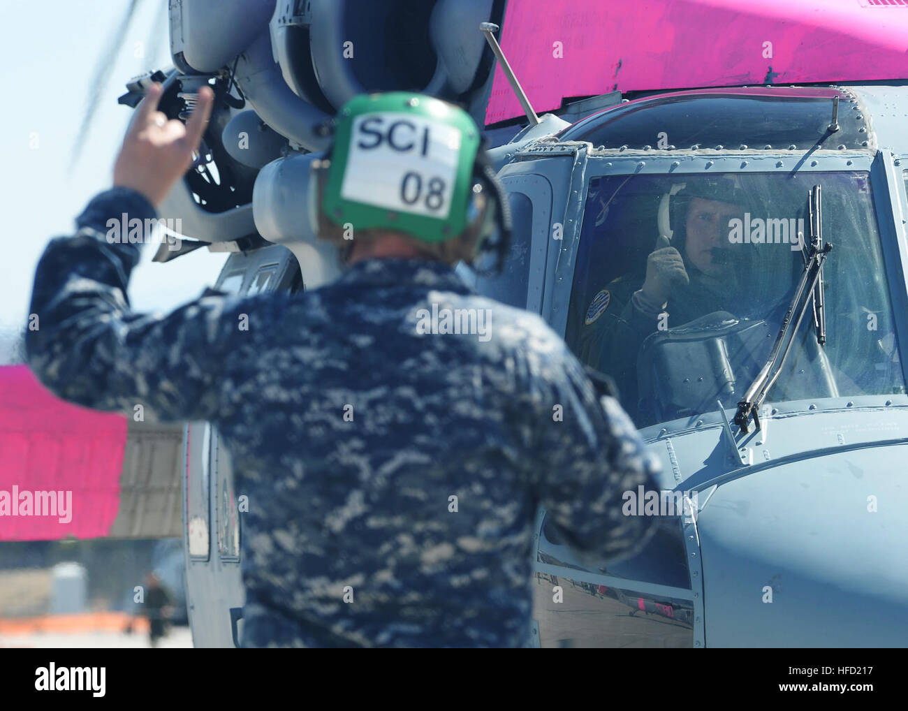 A U.S. Sailor with Helicopter Sea Combat Squadron (HSC) 3 signals the ...