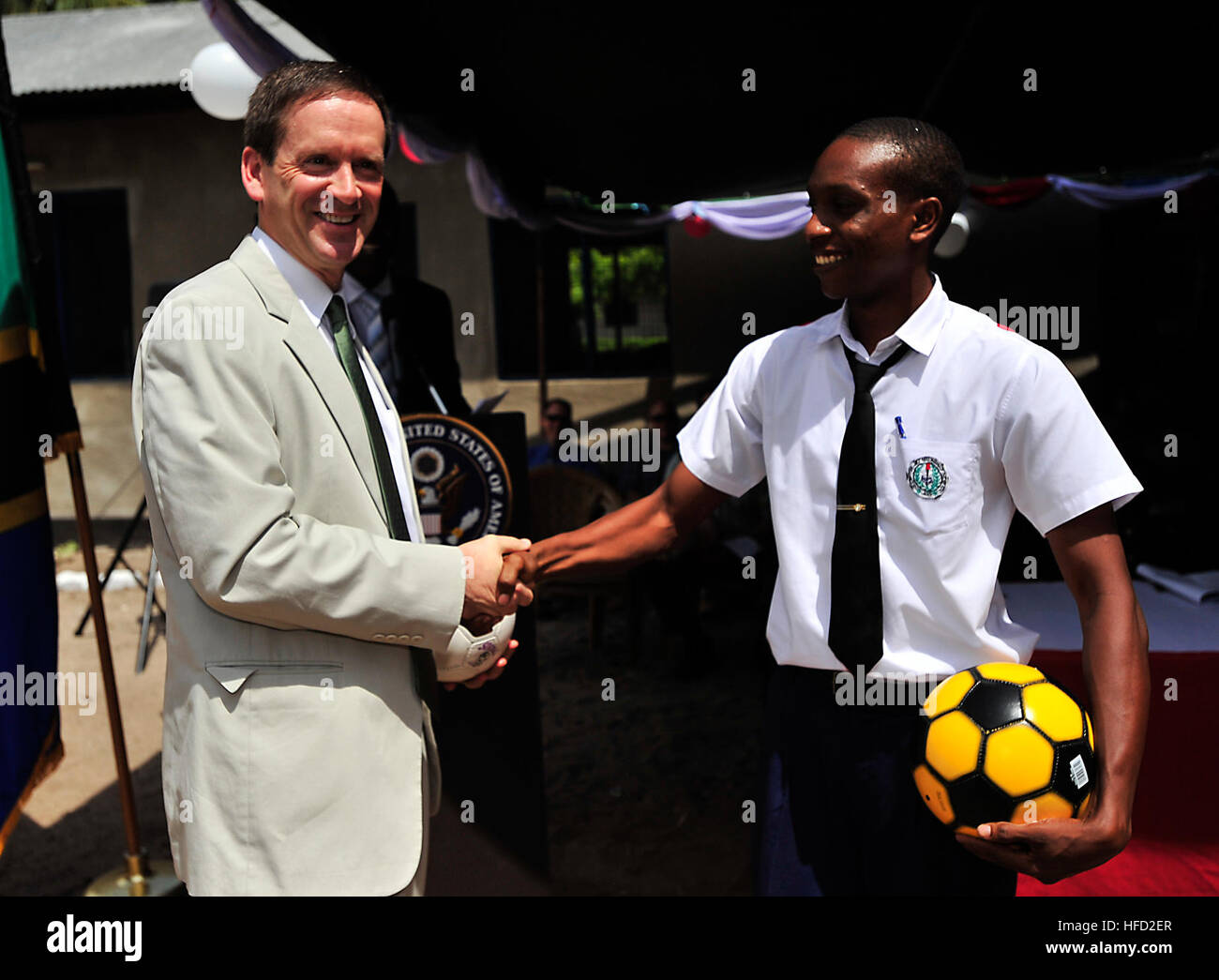 U.S. Ambassador to Tanzania, Mark Green, left, presents a student with ...