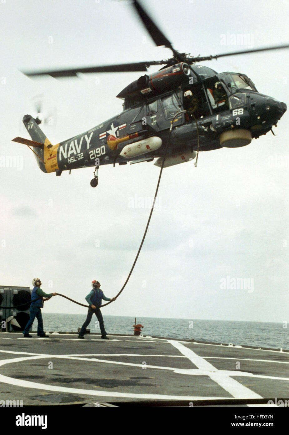 An SH-2F Seasprite LAMPS helicopter from HSL-32 hovers above the flight ...