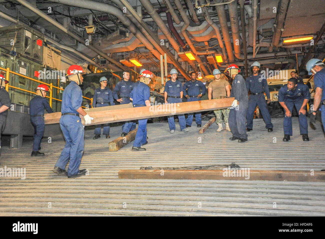Sailors remove shoring from the well deck of the amphibious assault ...