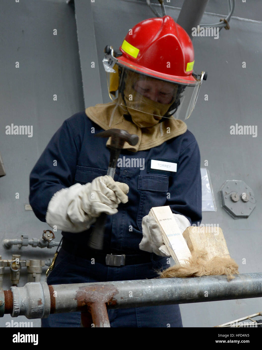 A U.S. Navy Damage Controlman installs a wooden wedge for a soft patch ...