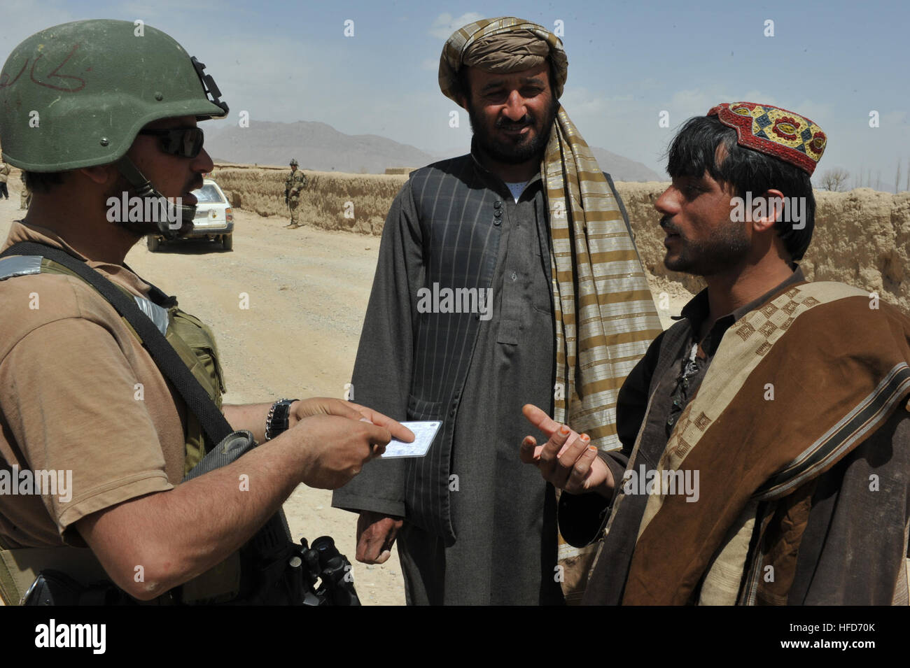 An Afghan National Army Special Forces Commando talks to two villagers ...