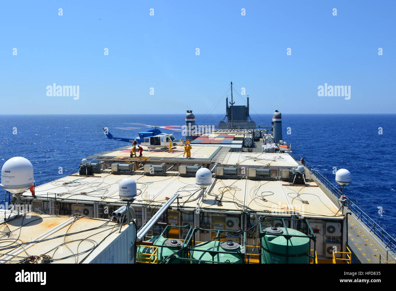 Crew members unload cargo from a helicopter aboard the container ship ...