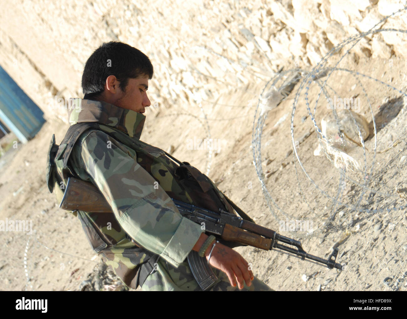 An Afghan national army soldier strings razor wire around a temporary ...