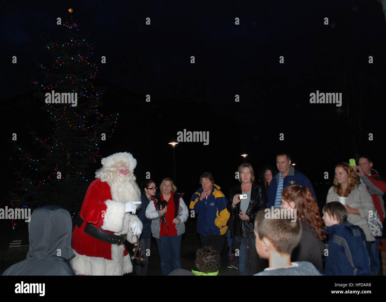 Bill Rode, dressed as Santa Claus, talks to sailors and their friends ...