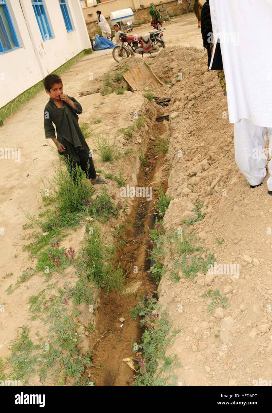 An Afghan boy stands next to a deteriorated, open sewer line in an out ...