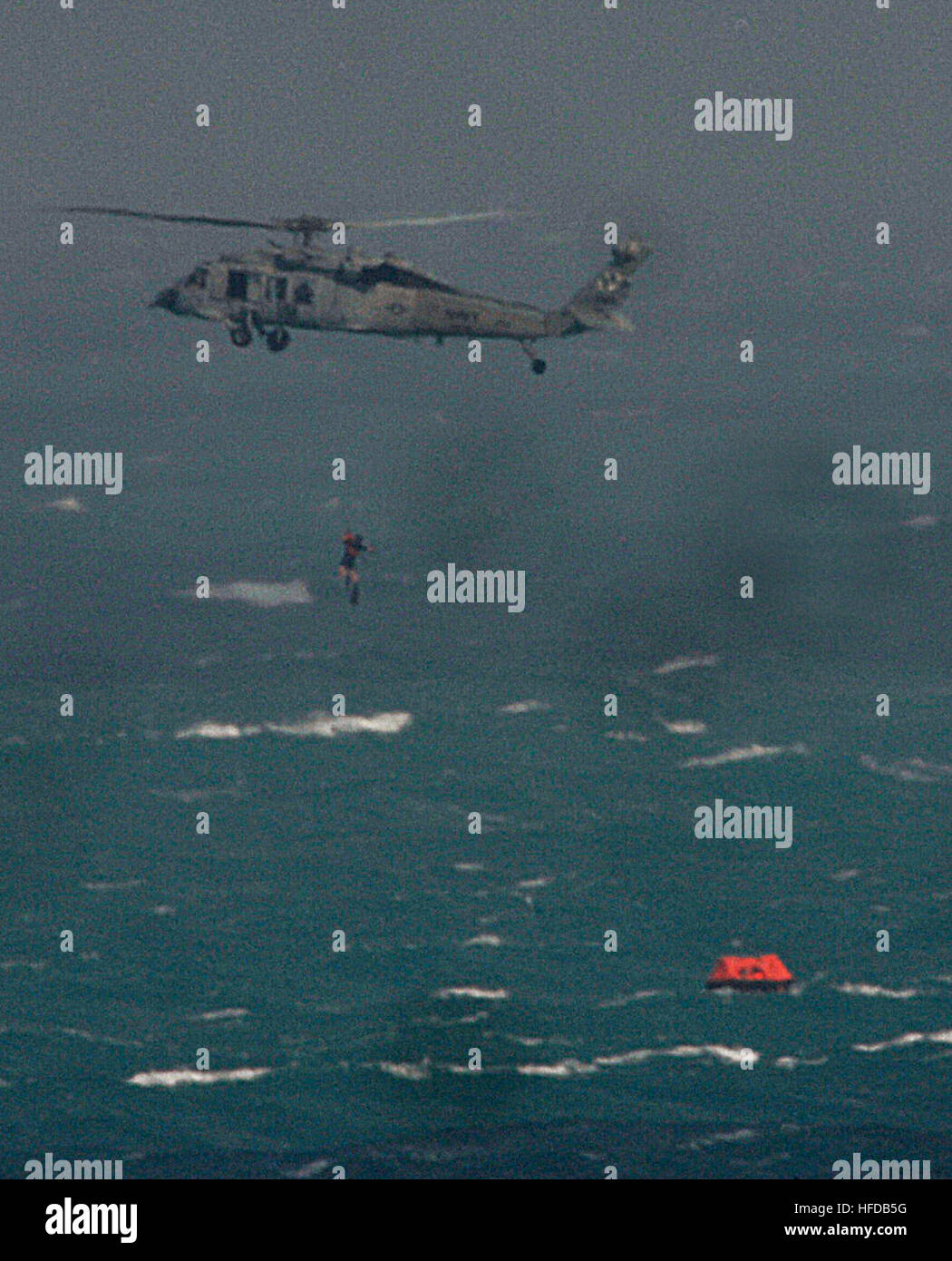 A Navy Search and Rescue swimmer descends from an SH-60S Seahawk ...