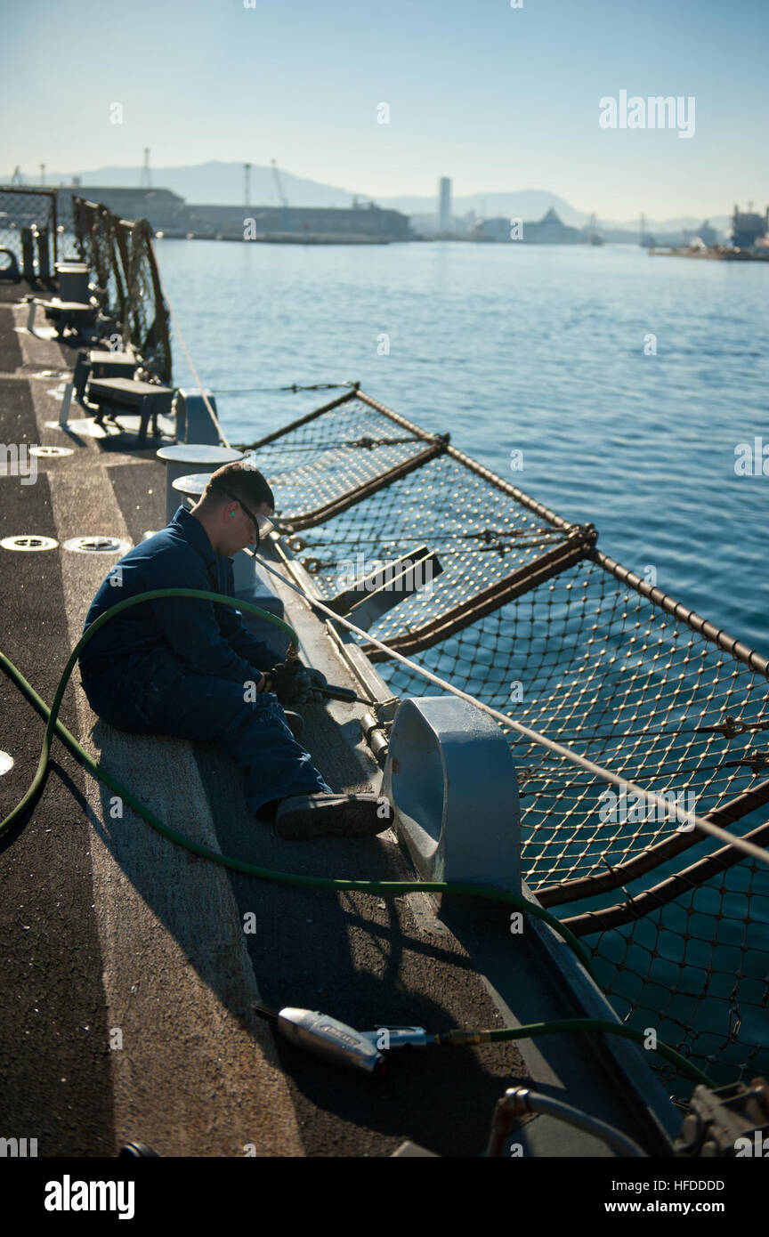 U.S. Navy Seaman Apprentice Kyle Freeman uses a needle gun to remove ...