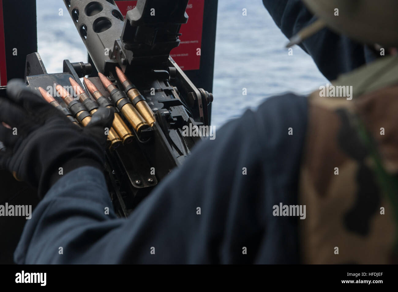 An Aviation Ordnanceman loads an M2HB .50-caliber machine gun on USS ...