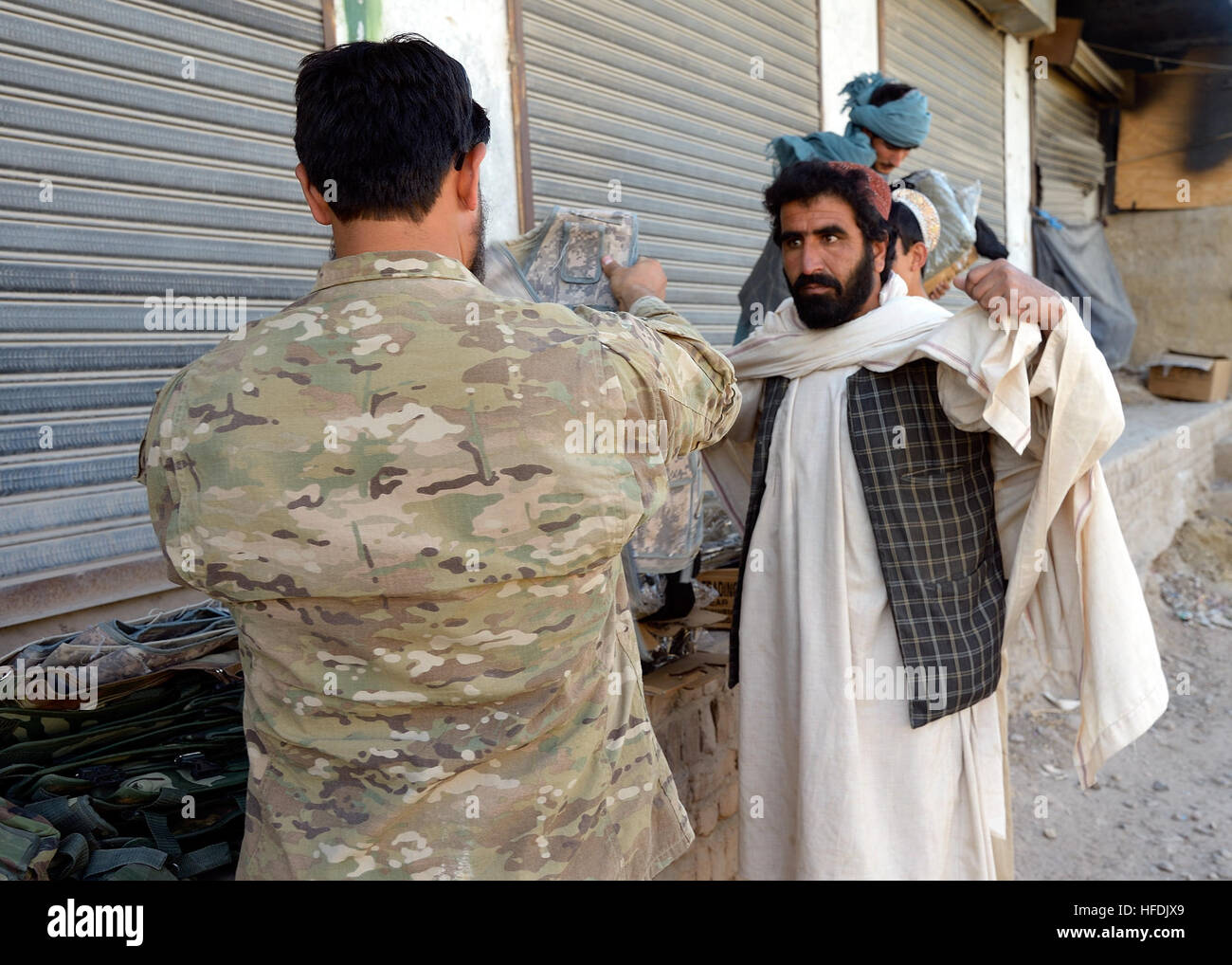 A coalition forces member gives a vest to an Afghan Local Police (ALP ...