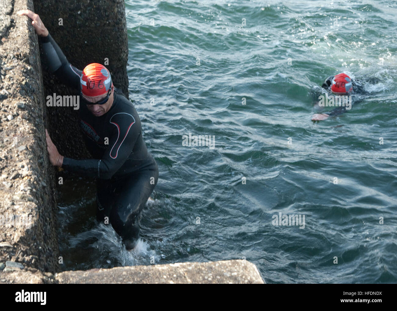 A participant from the Yokosuka 70.3 Triathlon climbs out of the water ...