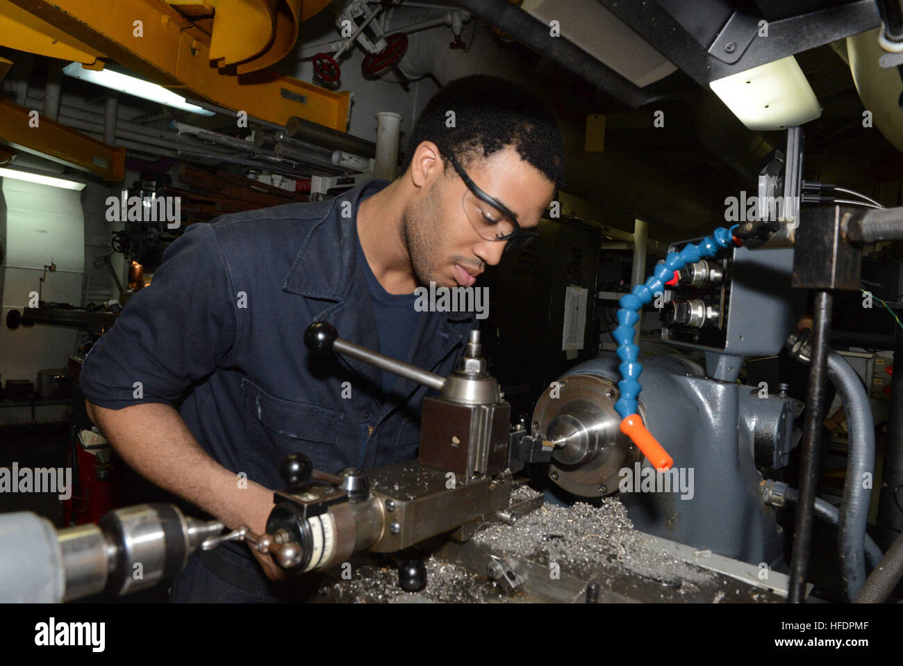 A machinery repairman uses an engine lathe aboard the amphibious ...