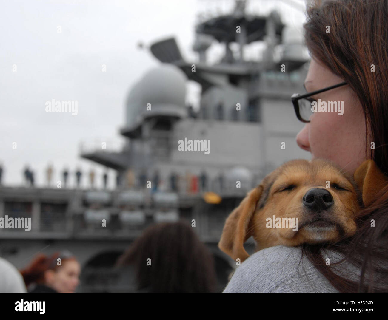 A loved one holds her sleepy dog while she watches USS Bataan depart ...