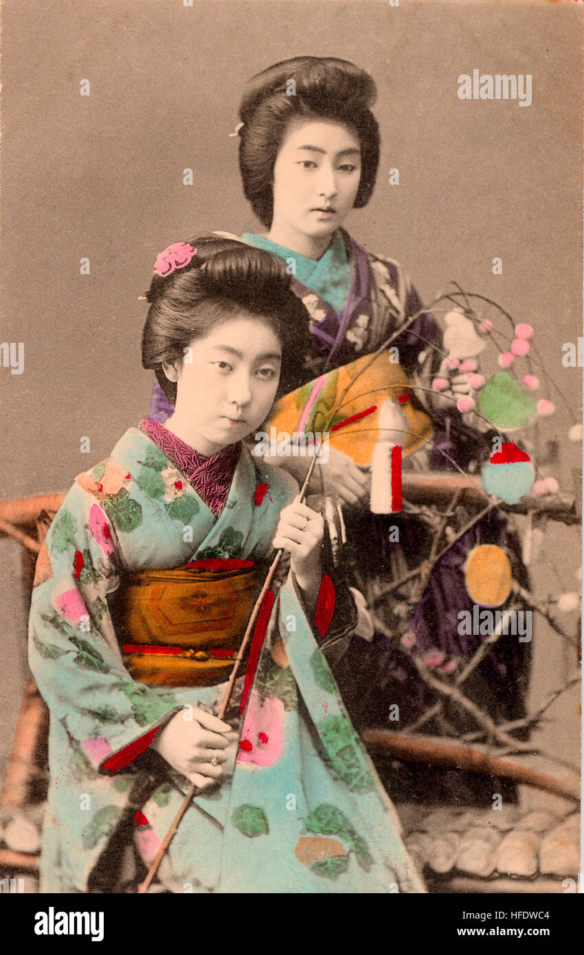 Circa 1900 sepia Japanese postcard. Women, geisha sitting golding sprig ...