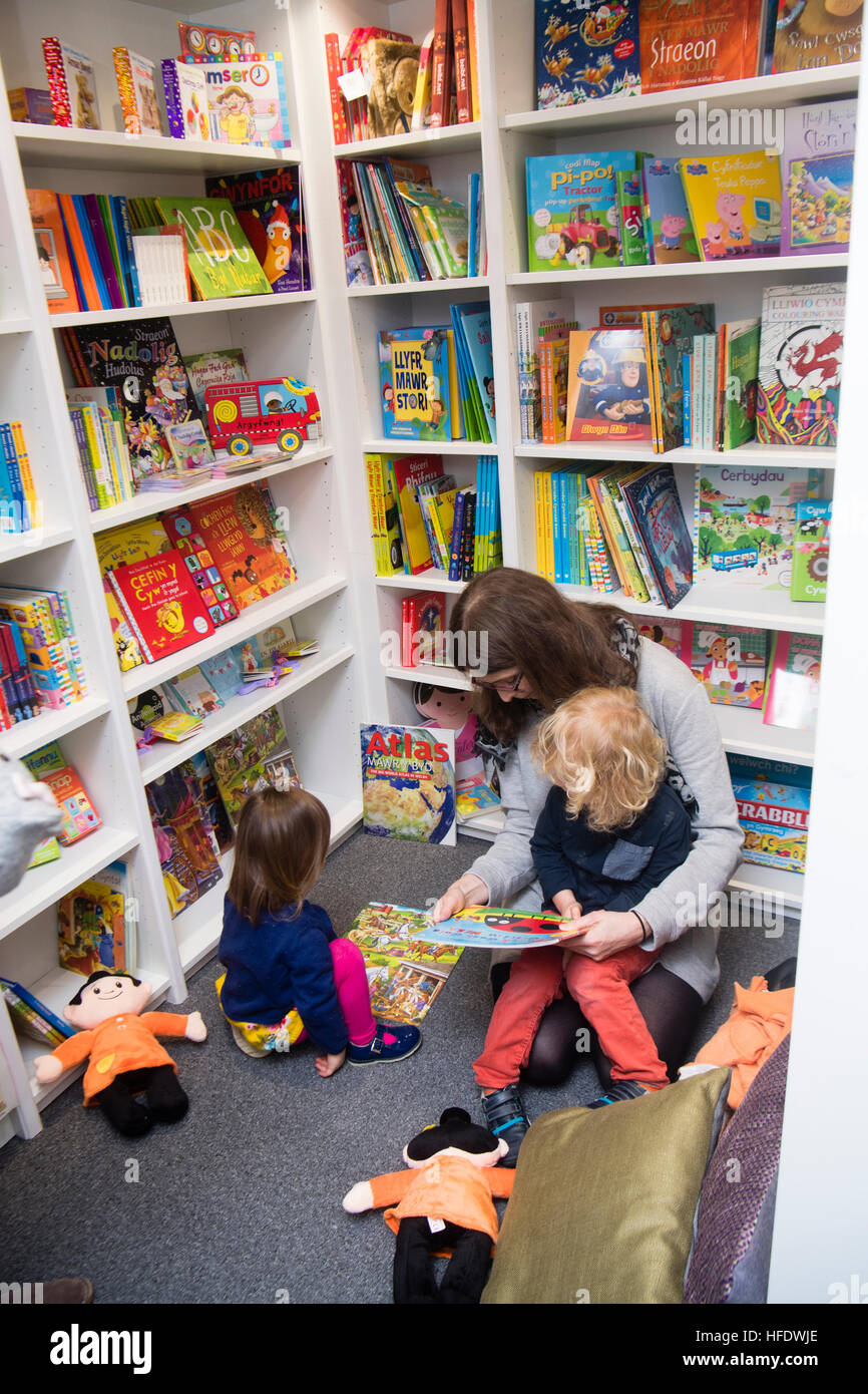 A mother reading a welsh laguage book to her children in Siop y Pethe ...