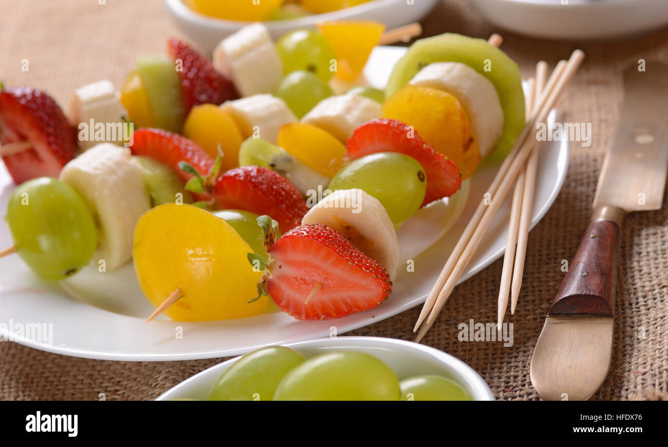 assorted fruit skewers with grapes, kiwi, banana, strawberry and plum ...