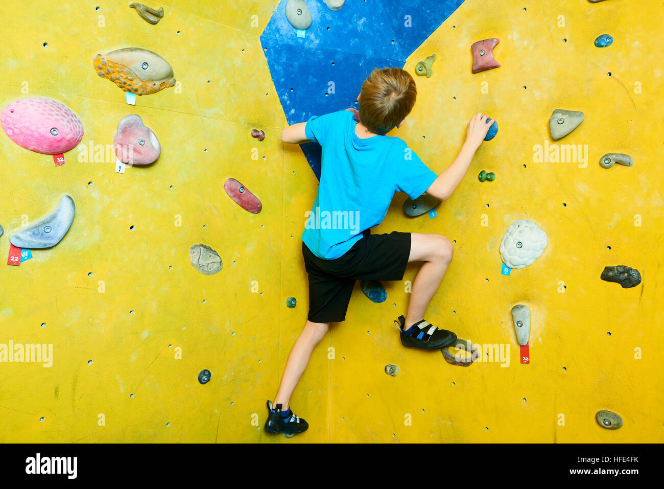 Free climber child young boy practicing on artificial boulders in gym ...