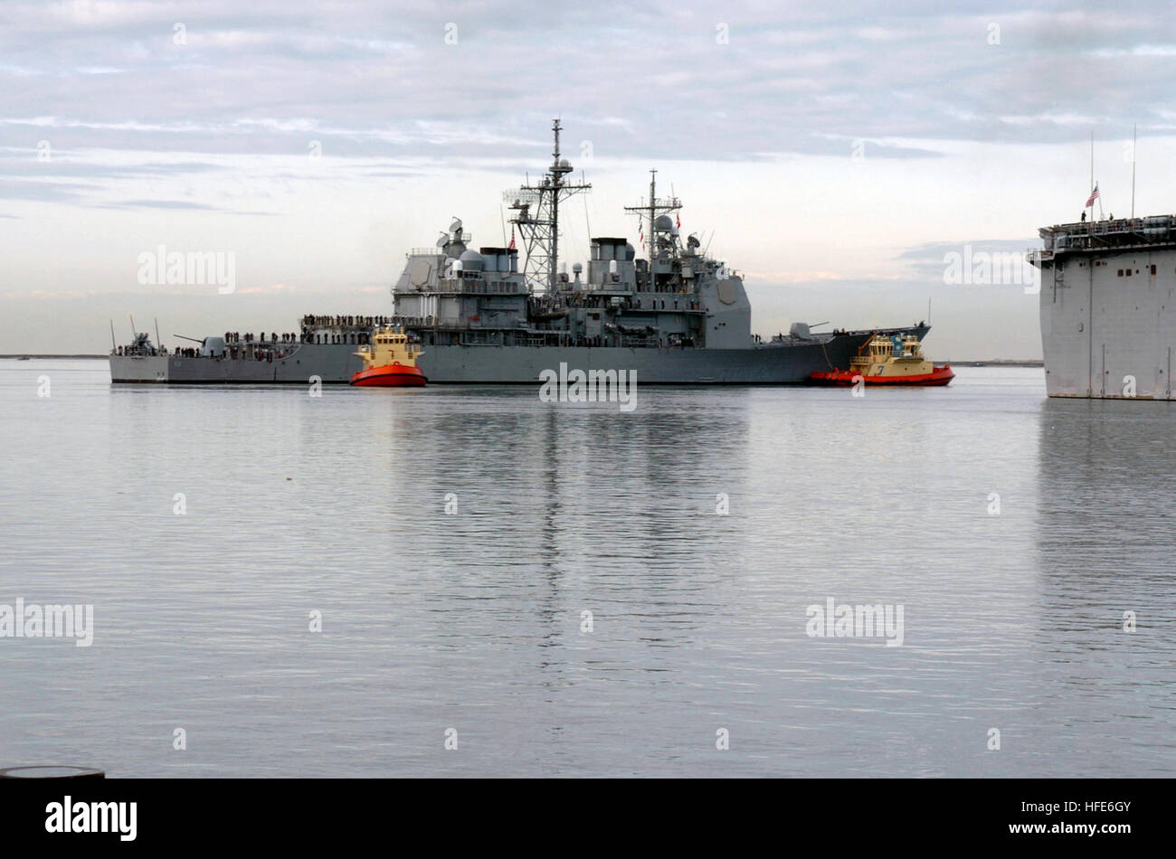 Two tug boats assist guided missile cruiser USS Bunker Hill (CG 52) as ...