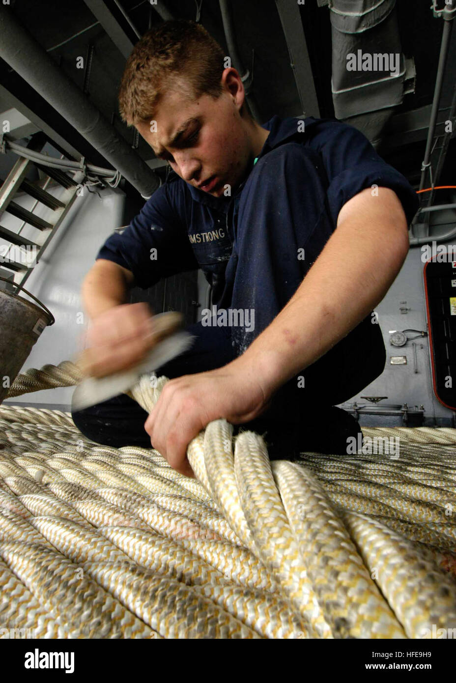 Crew member cleans a mooring line on the fantail of USS Abraham Lincoln ...