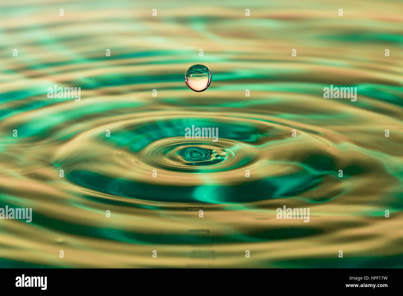 Water drop and waves on water with green background Stock Photo - Alamy