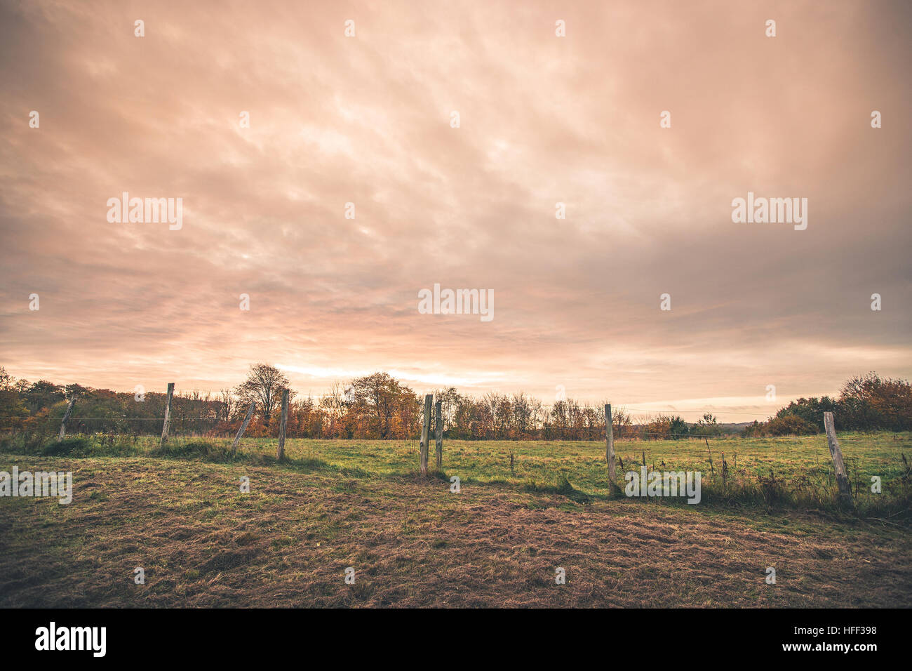 Countryside landscape with a wired fence on a field in the sunset in a ...