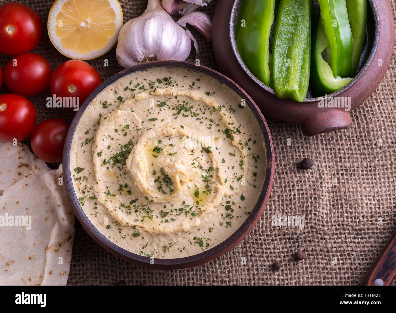 Humus in homemade bowl with vegetables on jute background. Top view ...