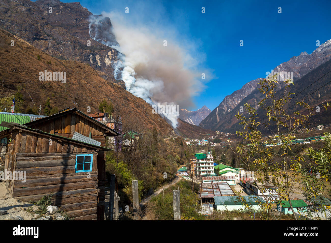 Forest fire burning on the hilly slopes in the small himalayan village ...