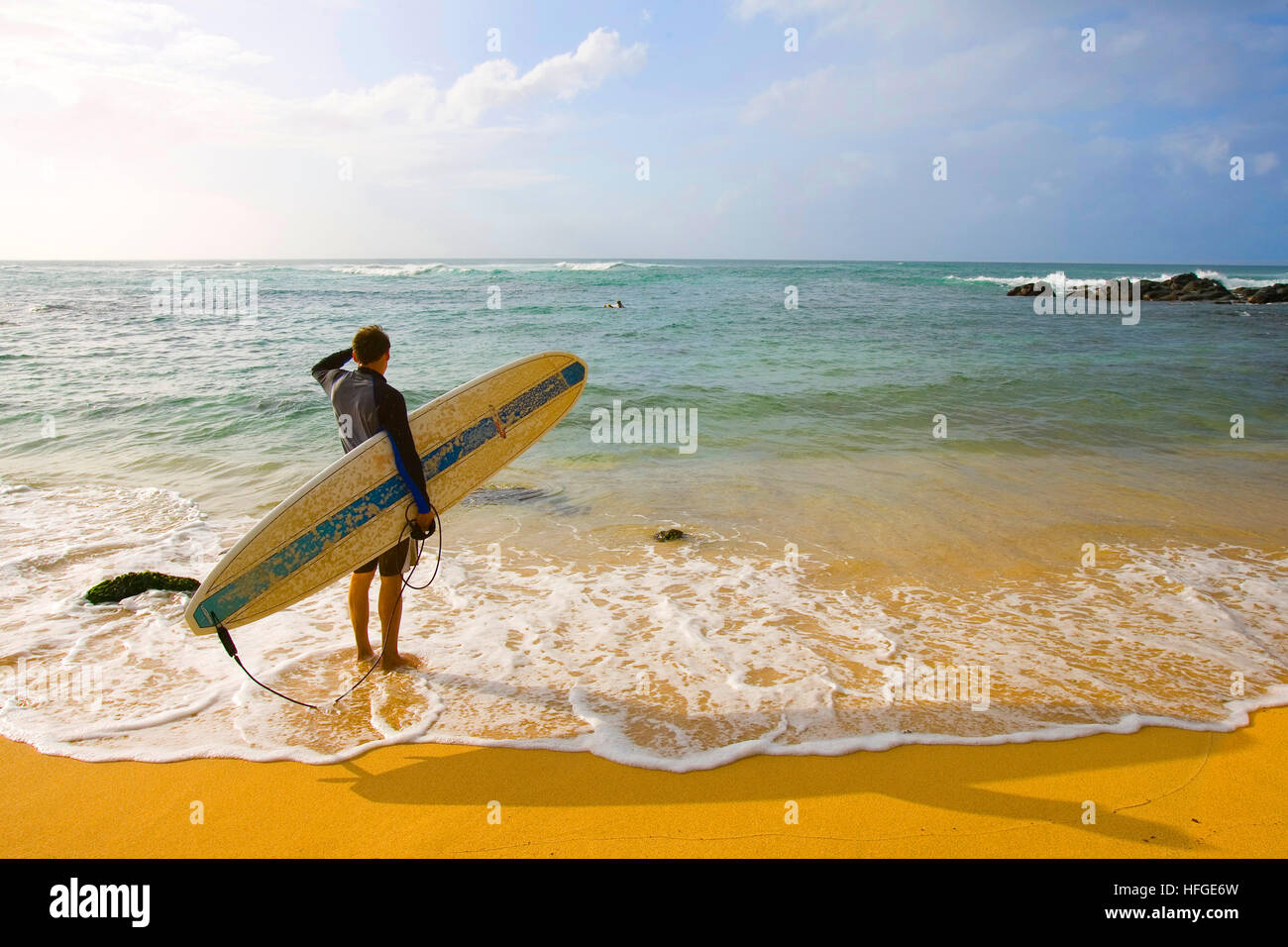 A Male Surfer holding his Surfboard and checking out the waves on a ...