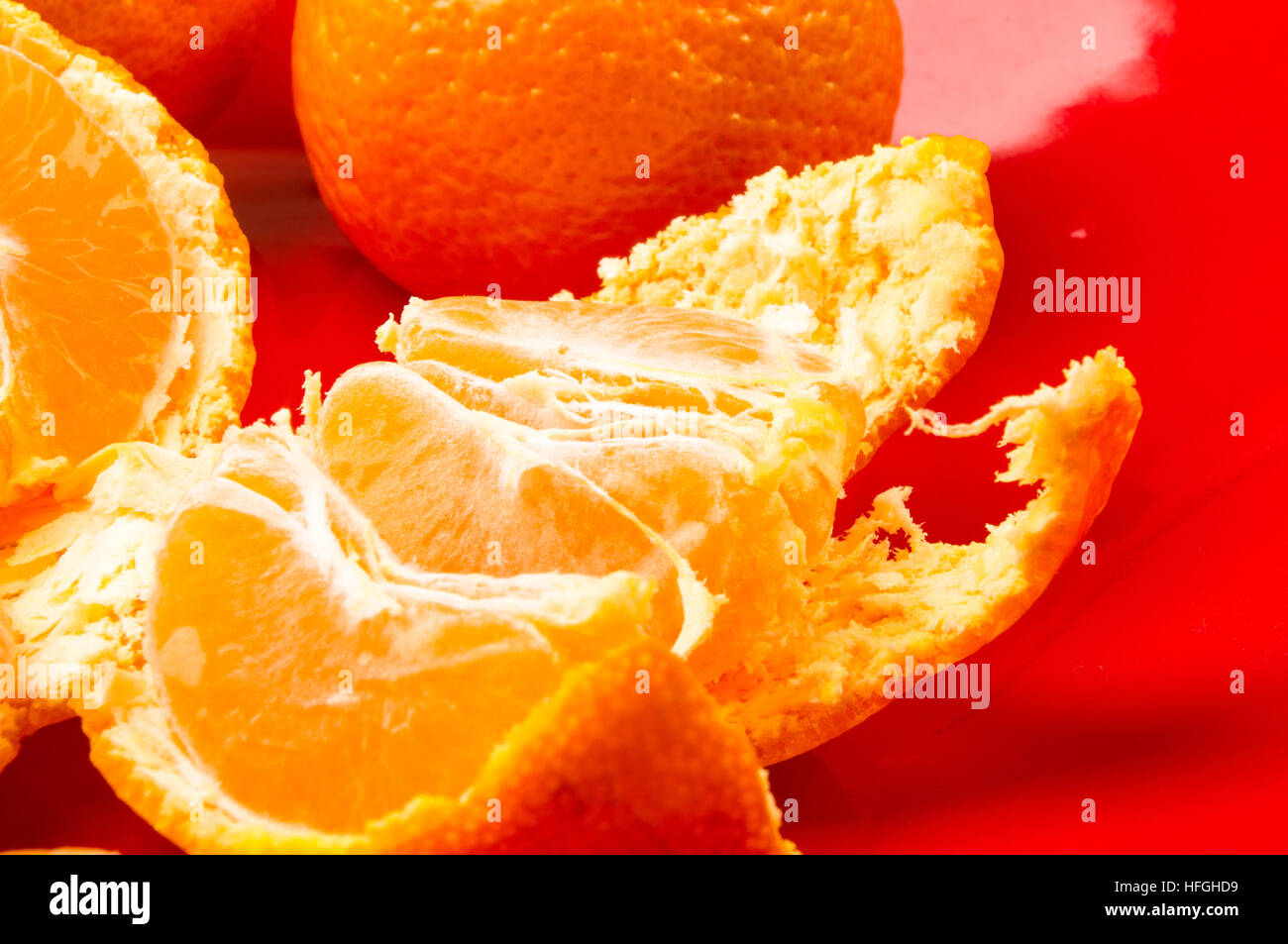 tangerines, peeled tangerine and tangerine slices in a red plate on ...