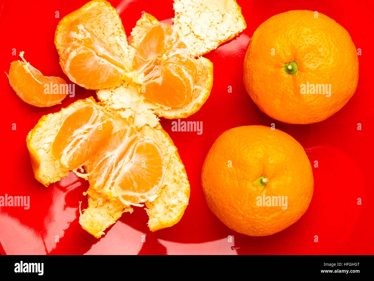 tangerines, peeled tangerine and tangerine slices in a red plate on ...