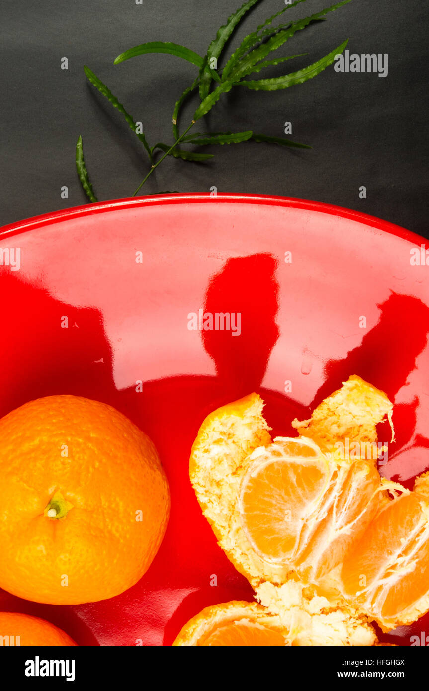 tangerines, peeled tangerine and tangerine slices in a red plate on ...