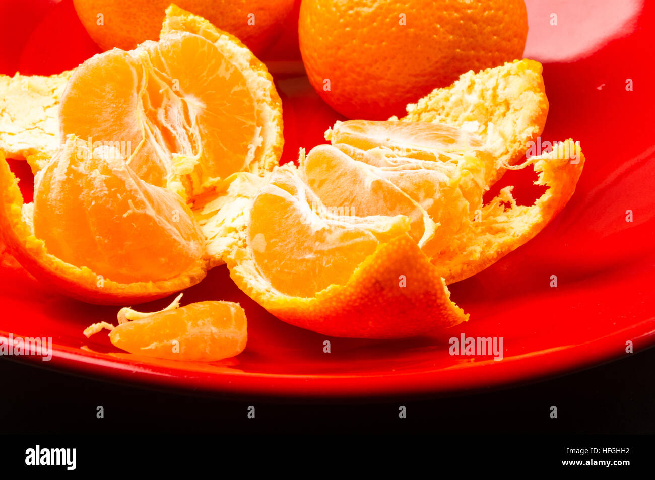 tangerines, peeled tangerine and tangerine slices in a red plate on ...