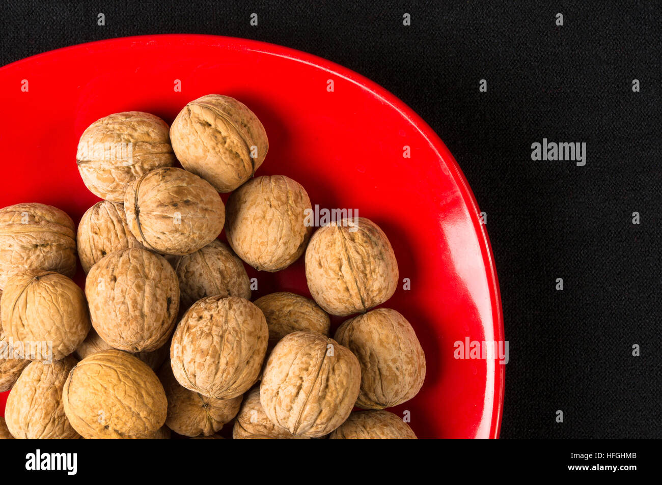 walnuts in red plate on black background Stock Photo - Alamy