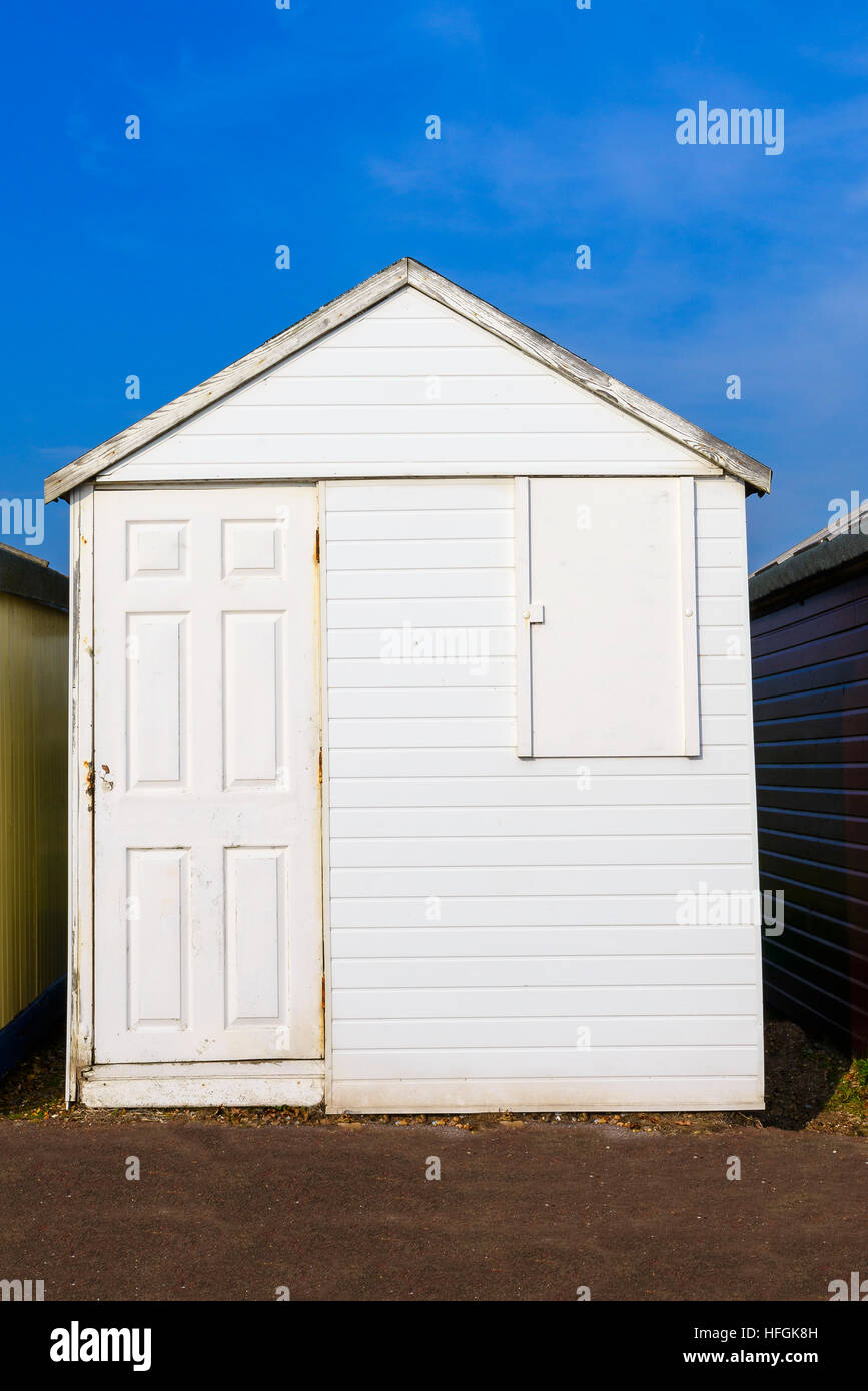 Old weathered white painted beach hut with blue sky background ...